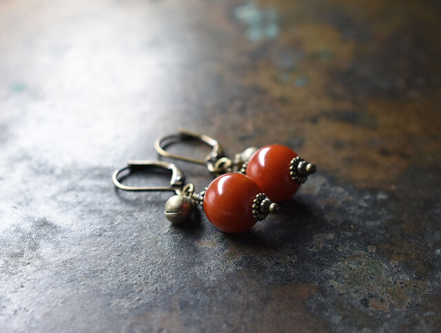 珊瑚色まん丸アフリカンアンバーと民族鈴のピアス(1.1mm) | iichi ハンドメイド・クラフト作品・手仕事品の通販